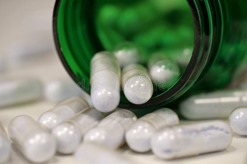 Capsules with Blue Powder Scattered on the Table. Open Green Container ...