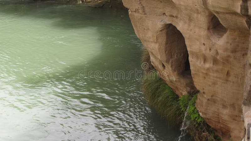 Stream Flowing from a Rocky Cave into a Calm River Stock Photo - Image ...