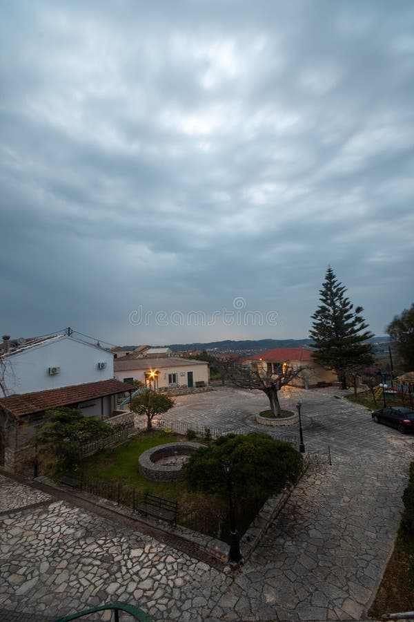 Cloudy View of a Small Town Square with Stone Paths, Lush Greenery, and ...