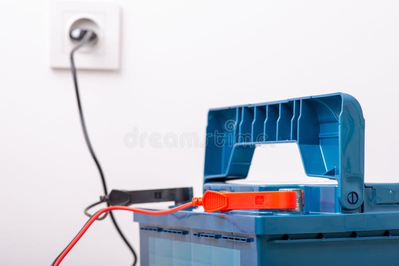Car Accumulator Battery Charging from the Socket Near White Wall Stock ...