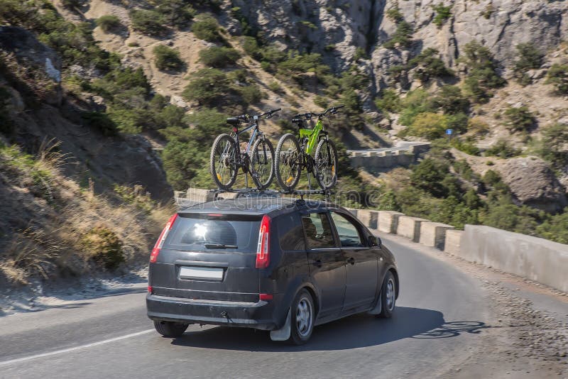 Car with Bicycles on the Upper Trunk Moves on a Road in the Mountains ...