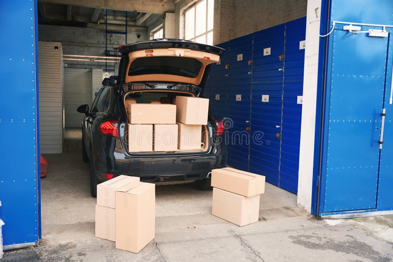 Car with Cardboard Boxes in the Trunk into a Warehouse with Self ...