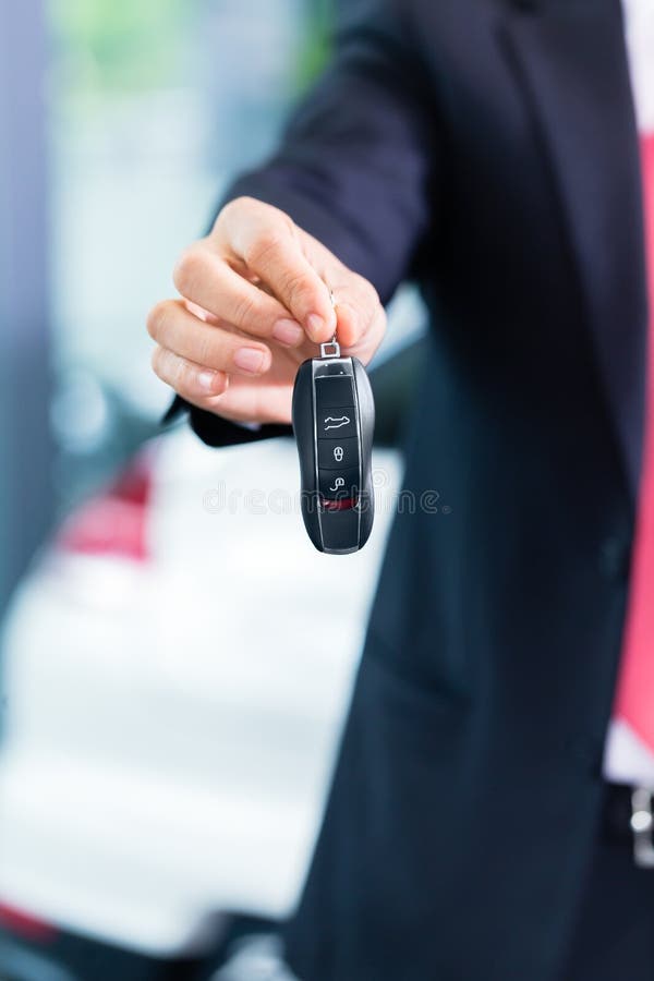 Dealer Handing Over Keys for New Car To Young Couple Stock Photo ...
