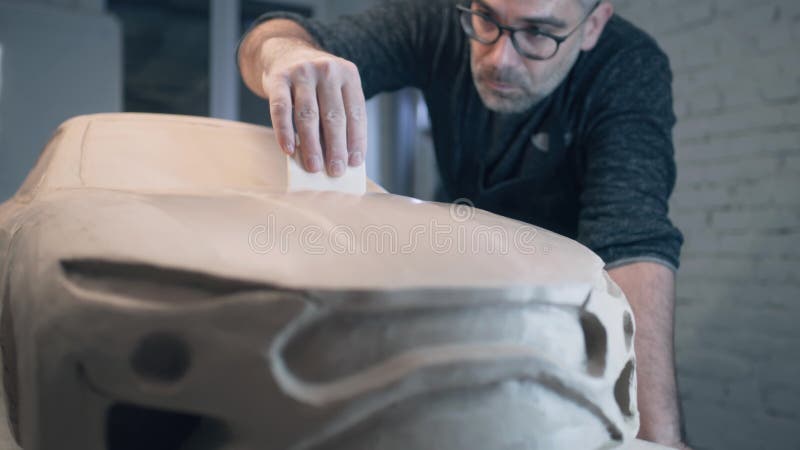 Car Designer Works on the Clay Sculpture of a Car Smooths Out Surface ...