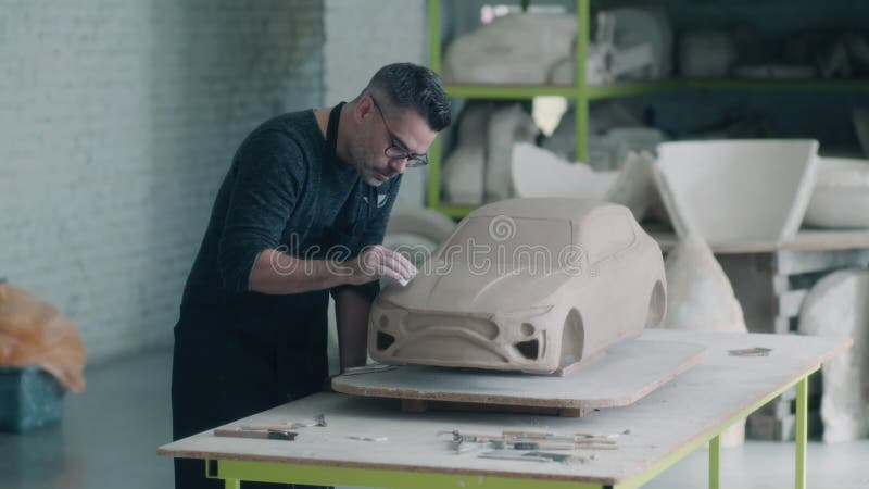 A Car Designer Works on Sculpture of Car with Shaping Tool To Smooth ...