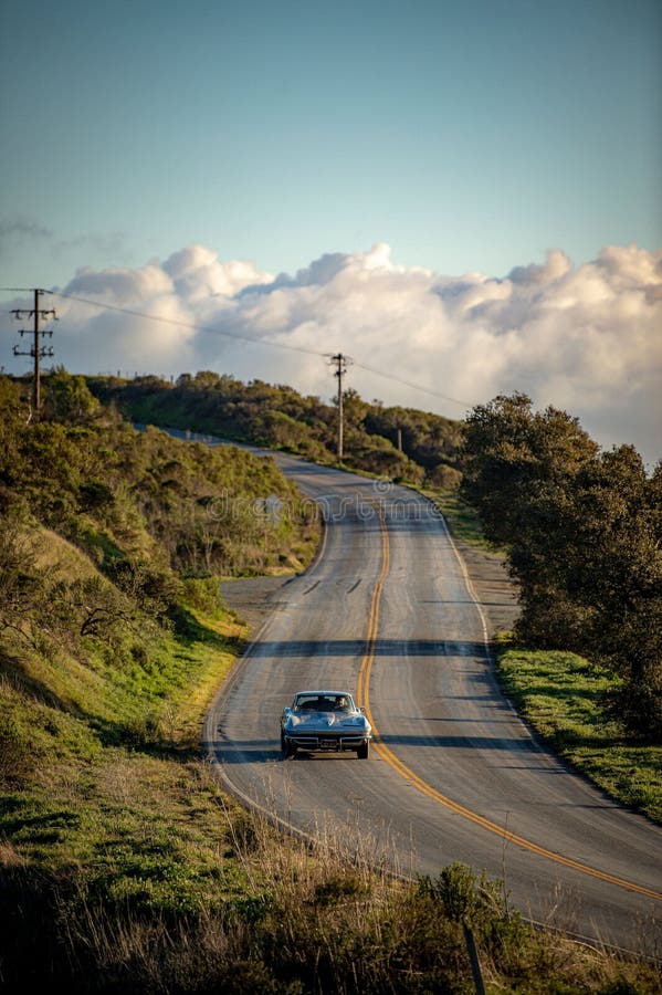 Car Driving on a Road with a Scenic Cloud Backdrop in the Background ...