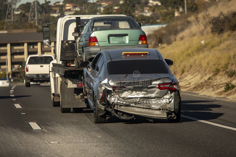 A Car with Extensive Rear End Damage Being Towed on a Freeway Stock ...