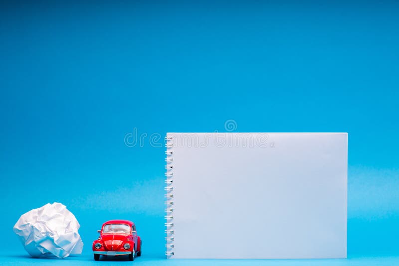 A Car Figurine between a Notebook and a Crumbled Sheet of Paper, on ...