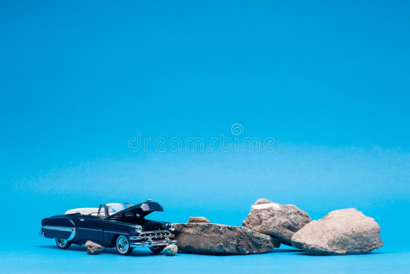 A Car with Its Hood Open Next To a Bunch of Stones, on Blue Background ...