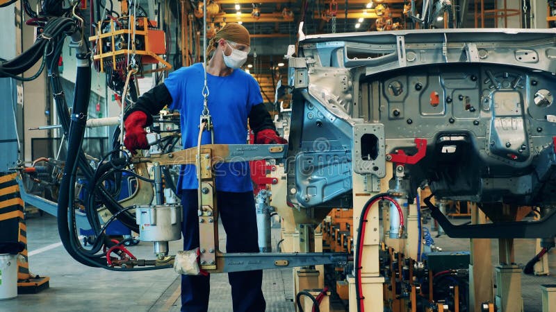 Car Manufacturing Worker Assembling a Car Body on an Assembling Line ...