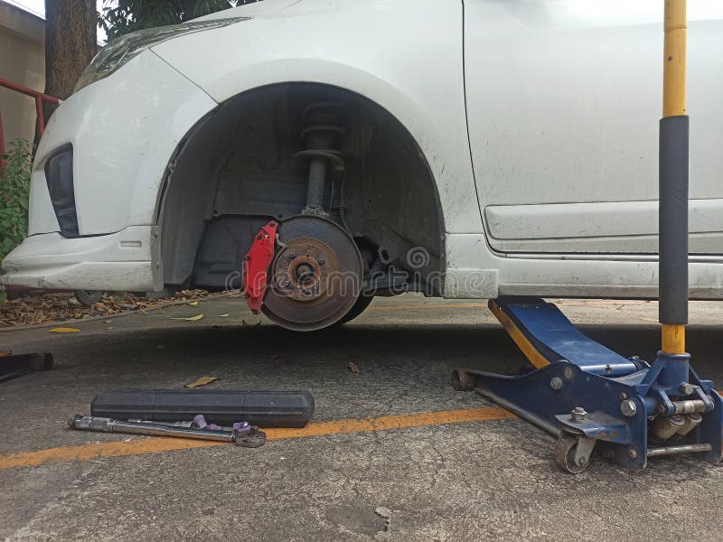 Car Mechanic Changing a Disc Brake on a Car in a Garage. Stock Image ...