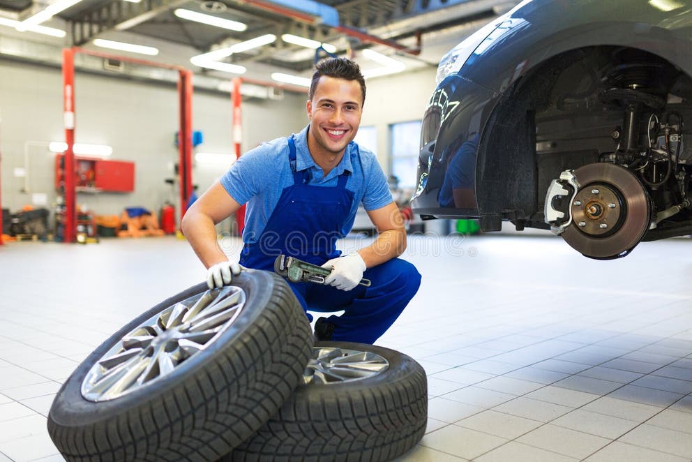 Car Mechanic Crouching Down by a Pair of Wheels Stock Image - Image of ...