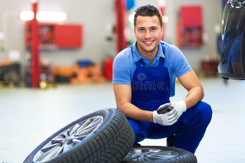 Car Mechanic Crouching Down by a Pair of Wheels Stock Photo - Image of ...