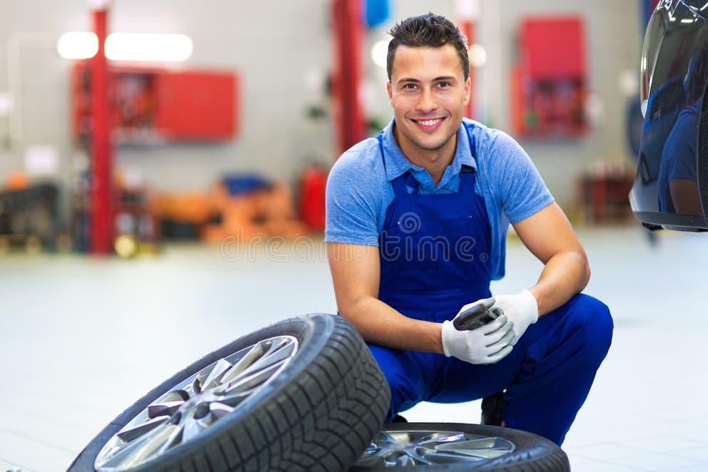 Car Mechanic Crouching Down by a Pair of Wheels Stock Photo - Image of ...