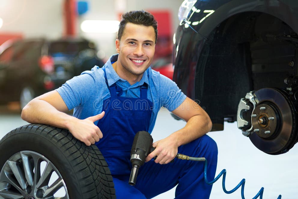 Car Mechanic Crouching Down by a Tire Stock Photo - Image of ...