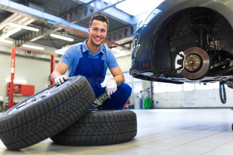 Car Mechanic Crouching Down by a Pair of Wheels Stock Photo - Image of ...
