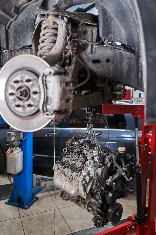 A Car Mechanic Inspects the Engine with a Flashlight. Engine Block on a ...