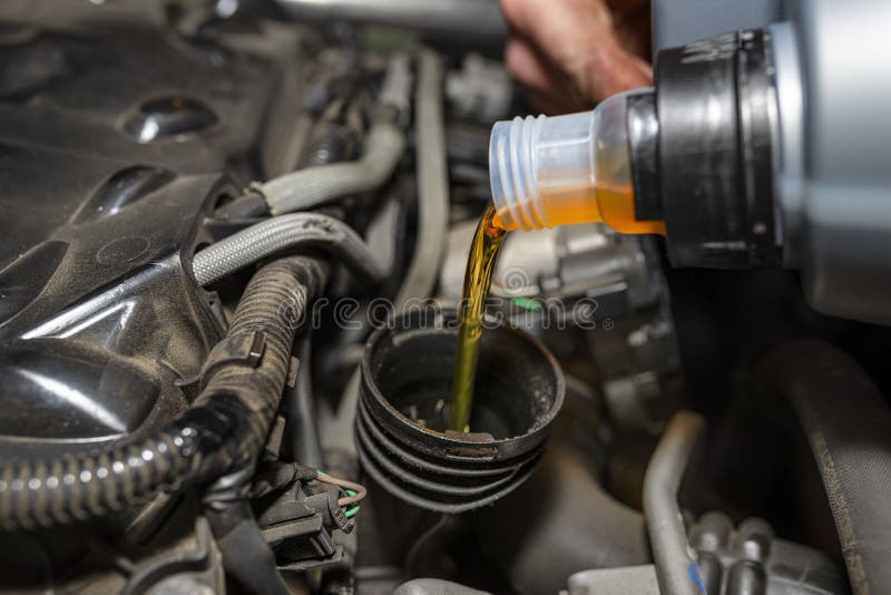 Car Mechanic Pours New Car Oil into the Engine from a Plastic Tank in a ...