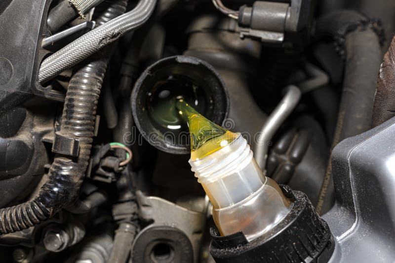 Car Mechanic Pours New Car Oil into the Engine from a Plastic Tank in a ...
