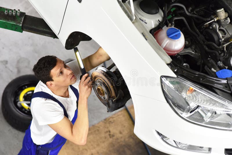 Car Mechanic Repairs Brakes of a Vehicle on the Lifting Platform in a ...