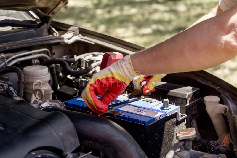 Car Mechanic Repairs a Car. a Mechanic Removes a Car Battery Stock ...
