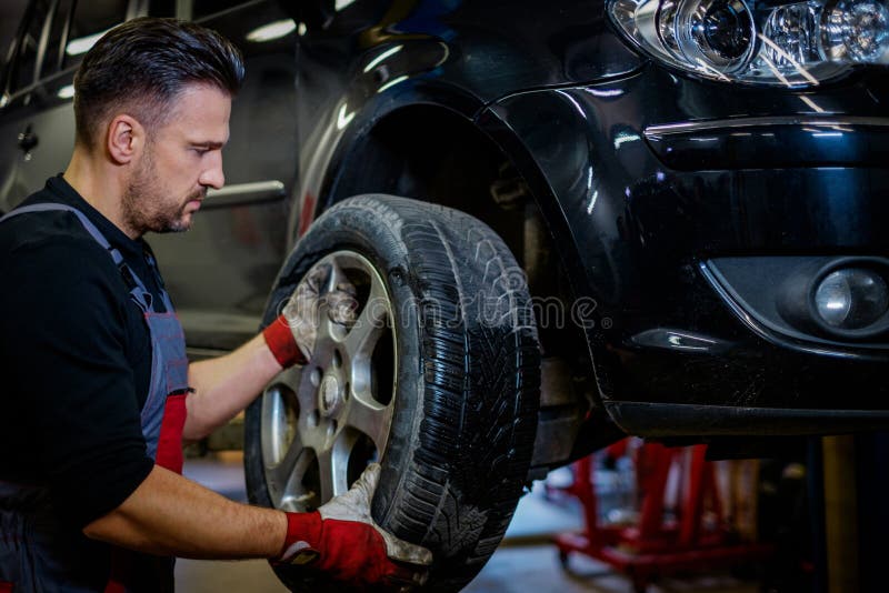 Car Mechanic Replacing Wheel in a Workshop Stock Image - Image of mount ...