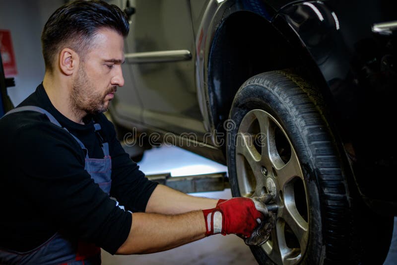 Car Mechanic Replacing Wheel in a Workshop Stock Image - Image of ...