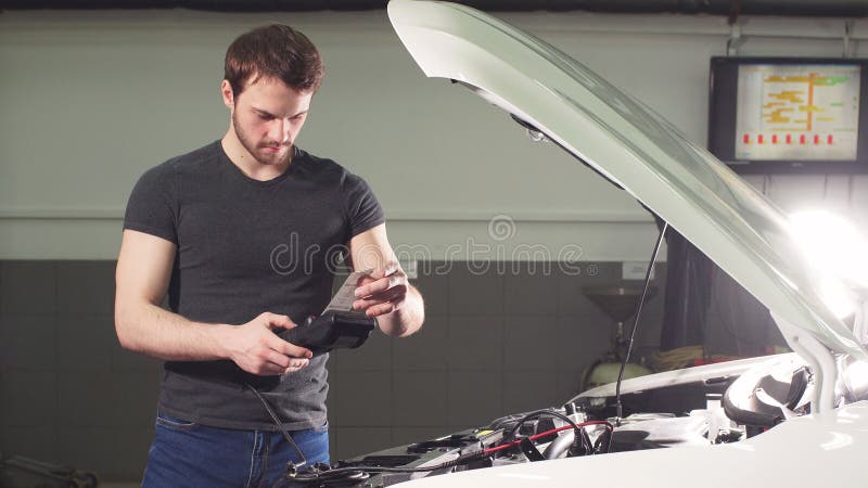 Car Mechanic Using Electrical Tool for Testing Car System in Garage ...