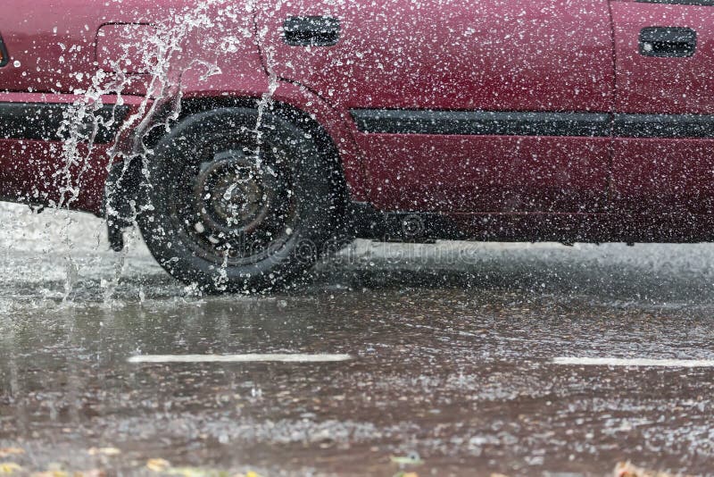 Car Motion through Big Puddle of Water Splashes from the Wheels on the ...