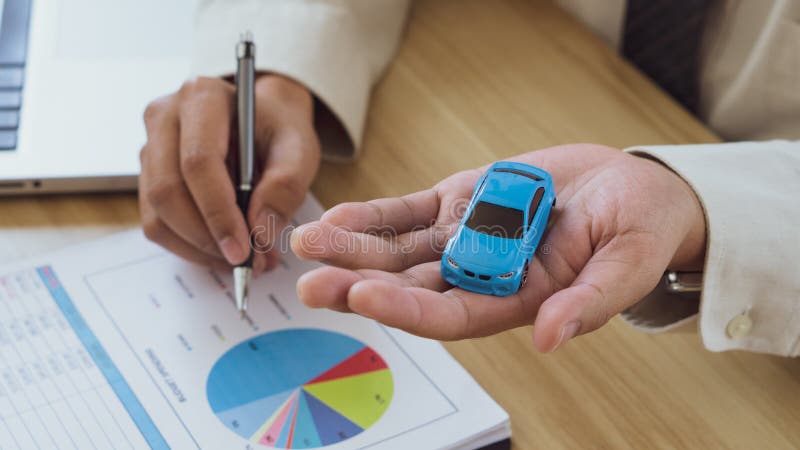 A Car Salesman Holds a Car Model and Explains the Use of the Car Stock ... A Car Salesman Holds a Car Model and Explains the Use of the Car Stock ...