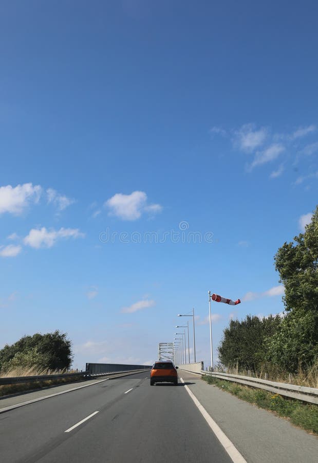 Car Speeding Over a Bridge and a Windsock Indicating the Direction ...