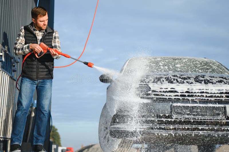 Car is Washed at a Professional Car Wash. Man Washes a Car with Foam ...