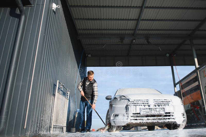 Car is Washed at a Professional Car Wash. Man Washes a Car with Foam ...