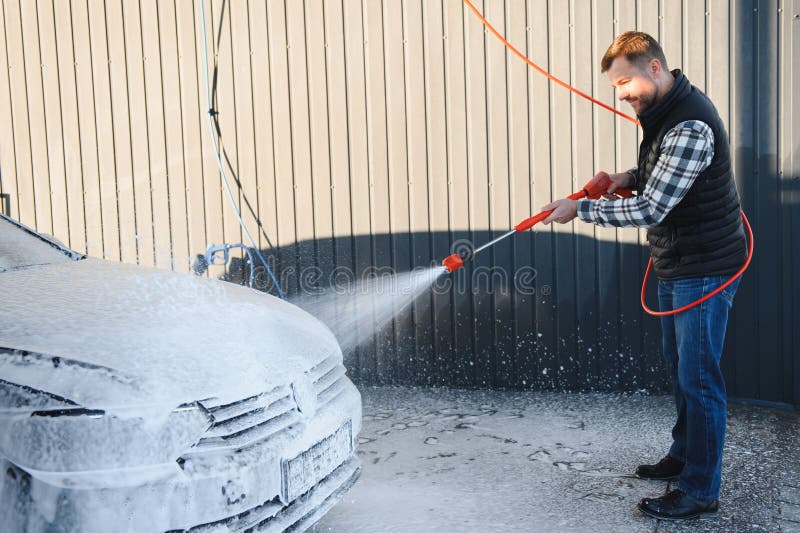 Car is Washed at a Professional Car Wash. Man Washes a Car with Foam ...