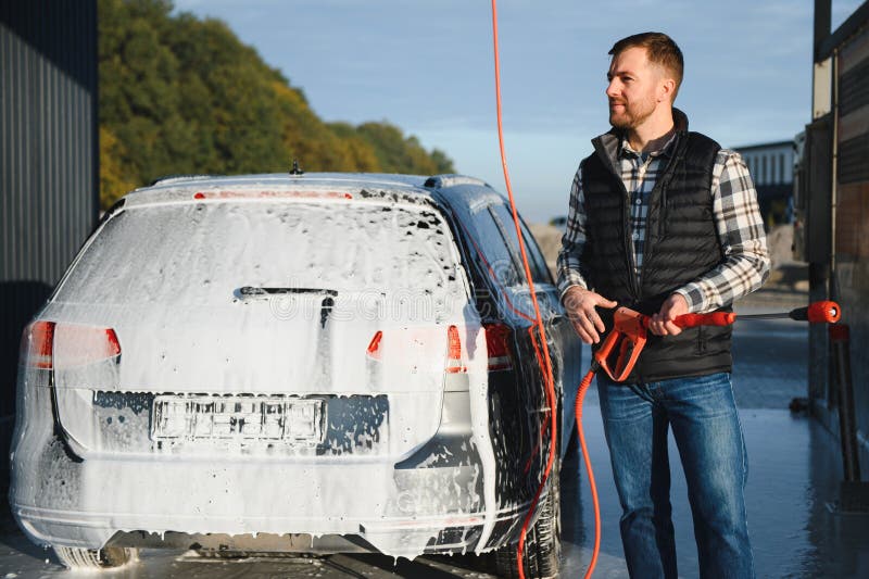 Car is Washed at a Professional Car Wash. Man Washes a Car with Foam ...