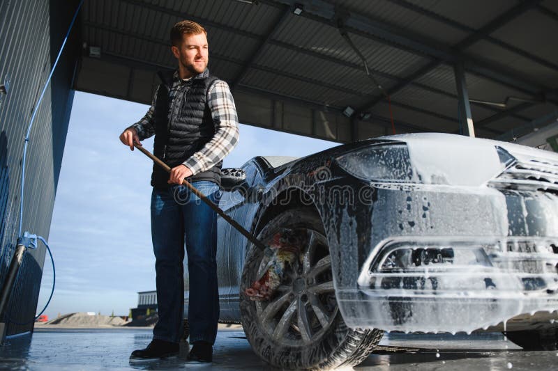 Car is Washed at a Professional Car Wash. Man Washes a Car with Foam ...