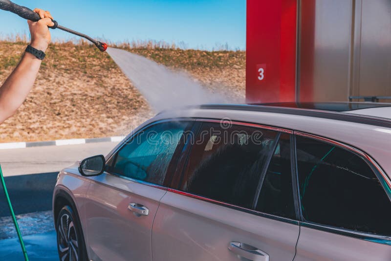 The Car is Washed at a Car Wash with a High Pressure Washer. High ...