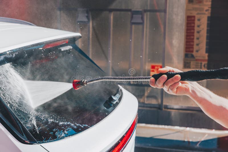 The Car is Washed at a Car Wash with a High Pressure Washer. High ...
