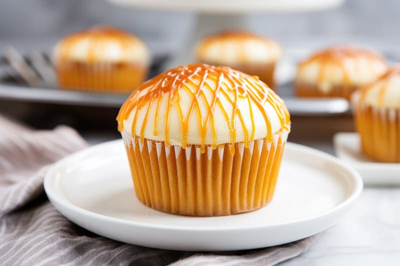 A Caramel-filled Vanilla Cupcake with Caramel Drizzle on Glass Dish ...