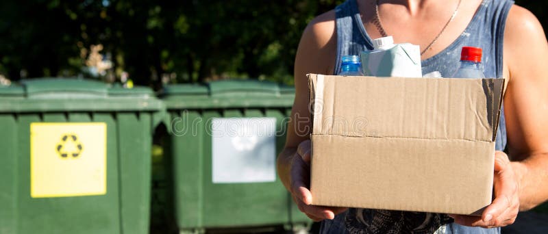 A Cardboard Box with Garbage in the Hands of a Man Near Containers for ...