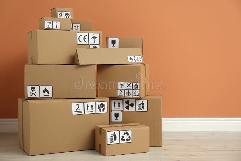 Cardboard Boxes with Packaging Symbols on Floor Near Orange Wall ...