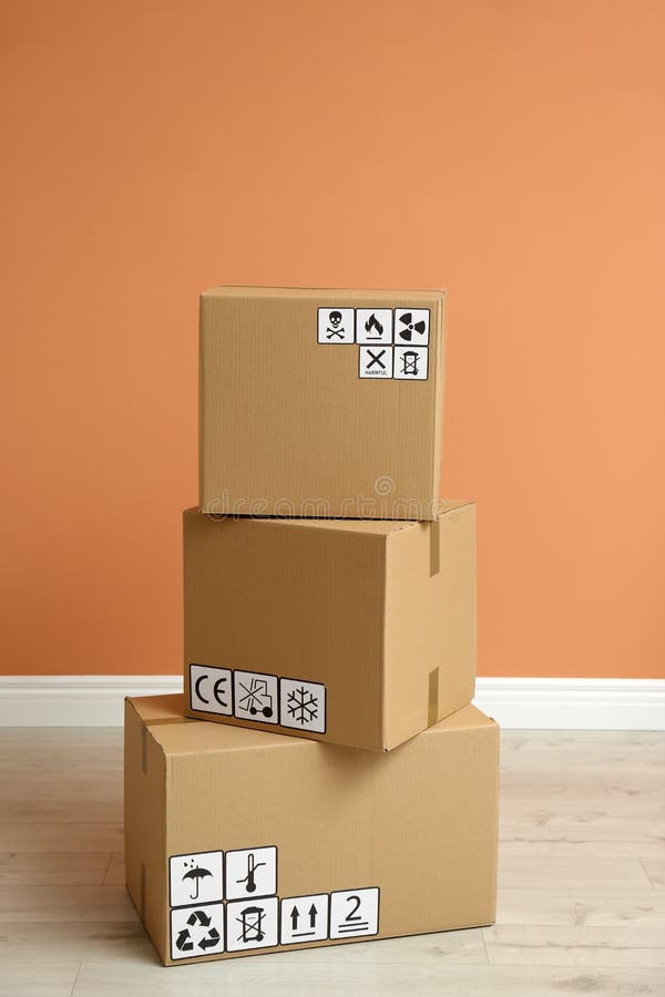 Cardboard Boxes with Packaging Symbols on Floor Near Orange Wall ...