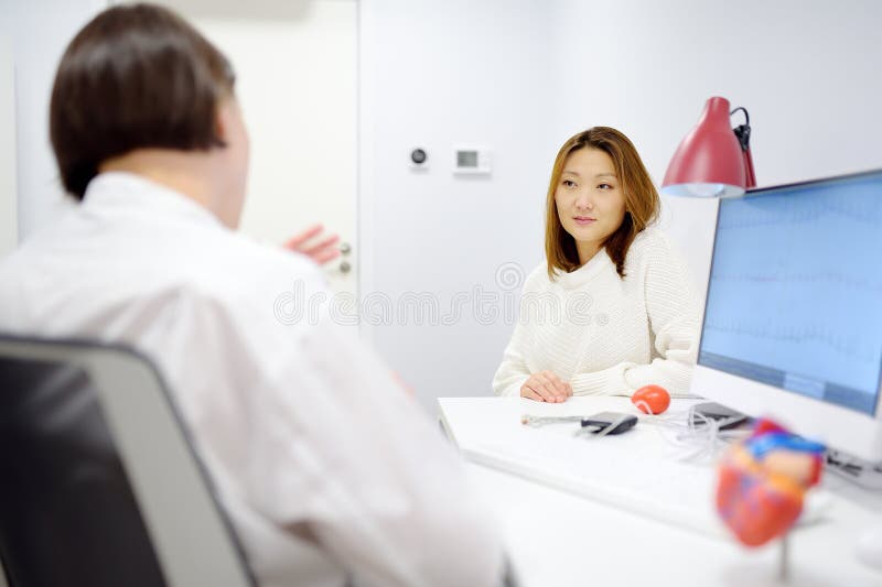 A Cardiologist during Appointment of Patient. Doctor Shows EKG on the ...