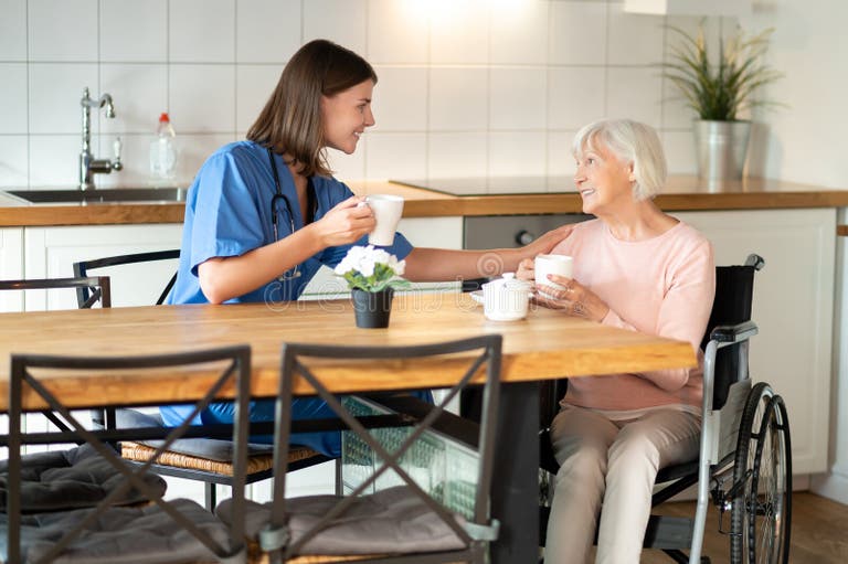 Care Assistant Feeding Elderly Lady and Both Looking Contented Stock ...