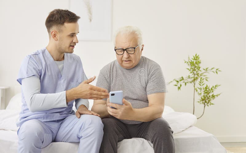 Caregiver Assisting Elderly Man with a Phone at Nursing Home Stock ...