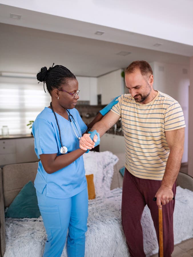 A Caregiver Helps a Patient Regain Mobility in a Home Stock Photo ...
