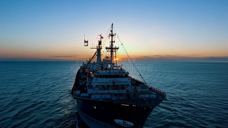 Cargo Ship Cutting through Ocean Waves at Dusk, with a Serene Sunset ...