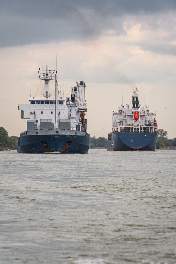 Cargo Ships Navigating a River Under a Cloudy Sky. Stock Photo - Image ...
