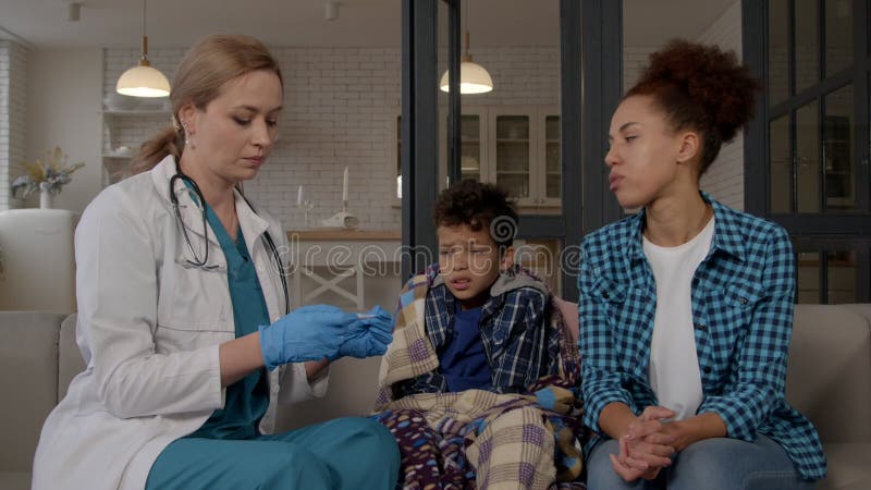 Caring Female General Practitioner Measuring Temperature of Sick Black ...