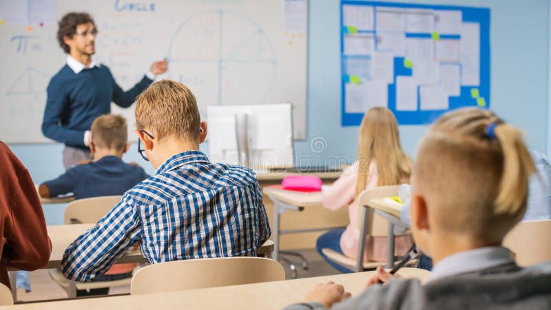 Caring Teacher Explains Lesson To a Classroom Full of Bright Diverse ...